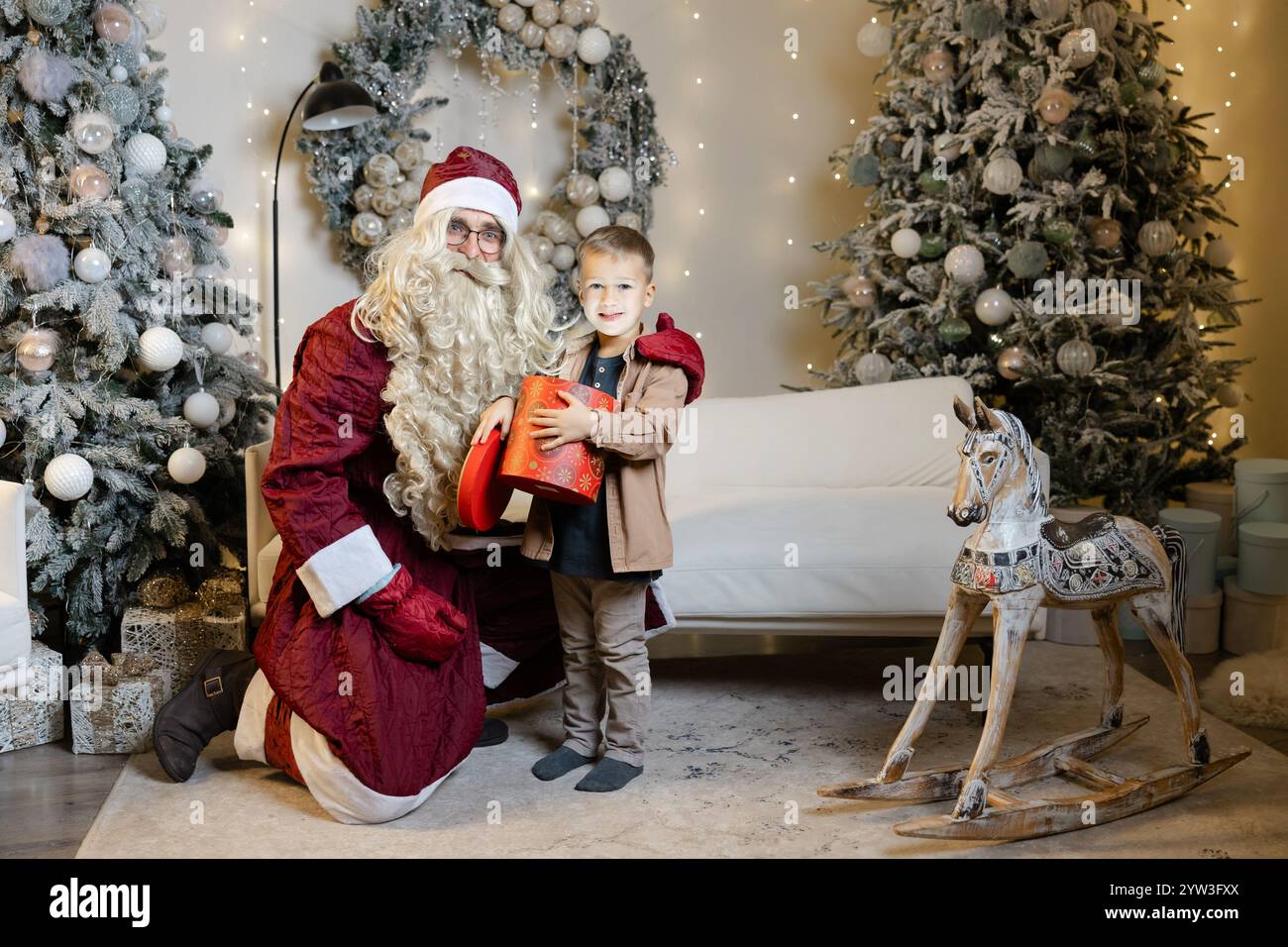 Santa claus handing a christmas present to a child in a room decorated ...