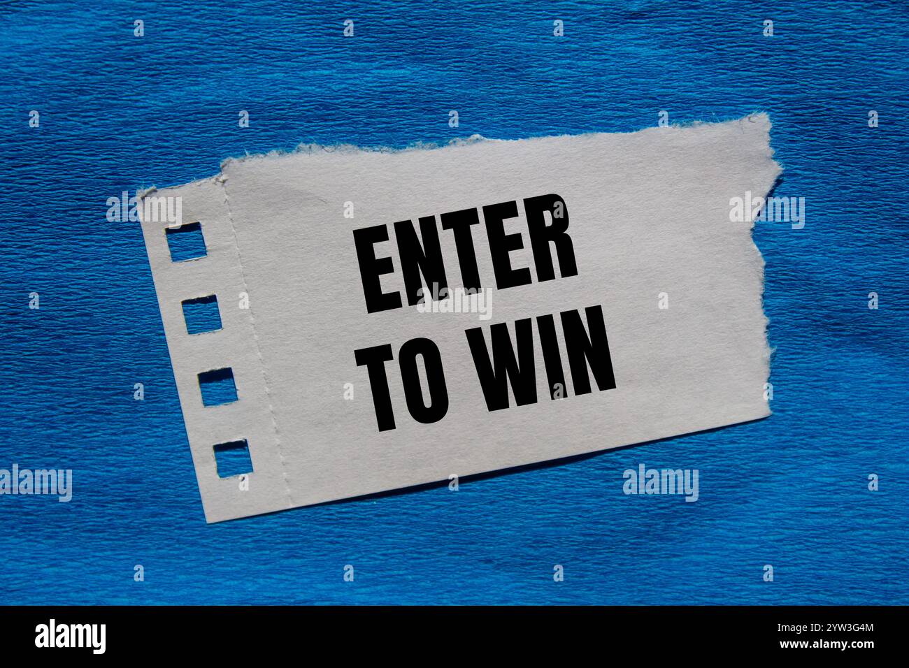 Enter to win message written on ripped torn paper piece with blue ...
