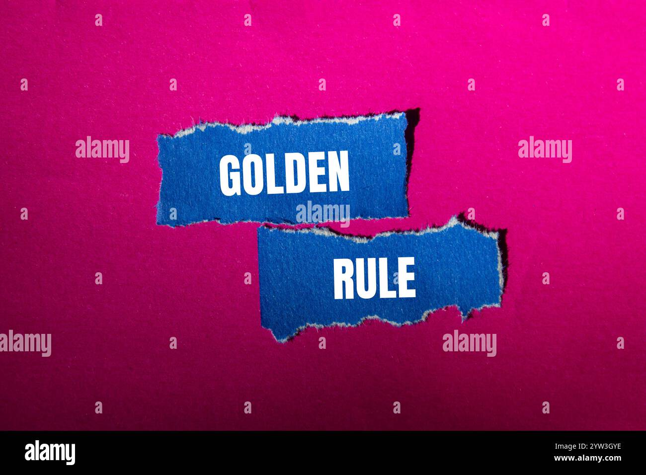 Golden rule message written on ripped torn blue paper pieces with pink ...