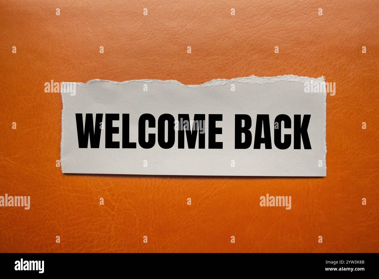 Welcome back message written on ripped torn paper piece with brown ...