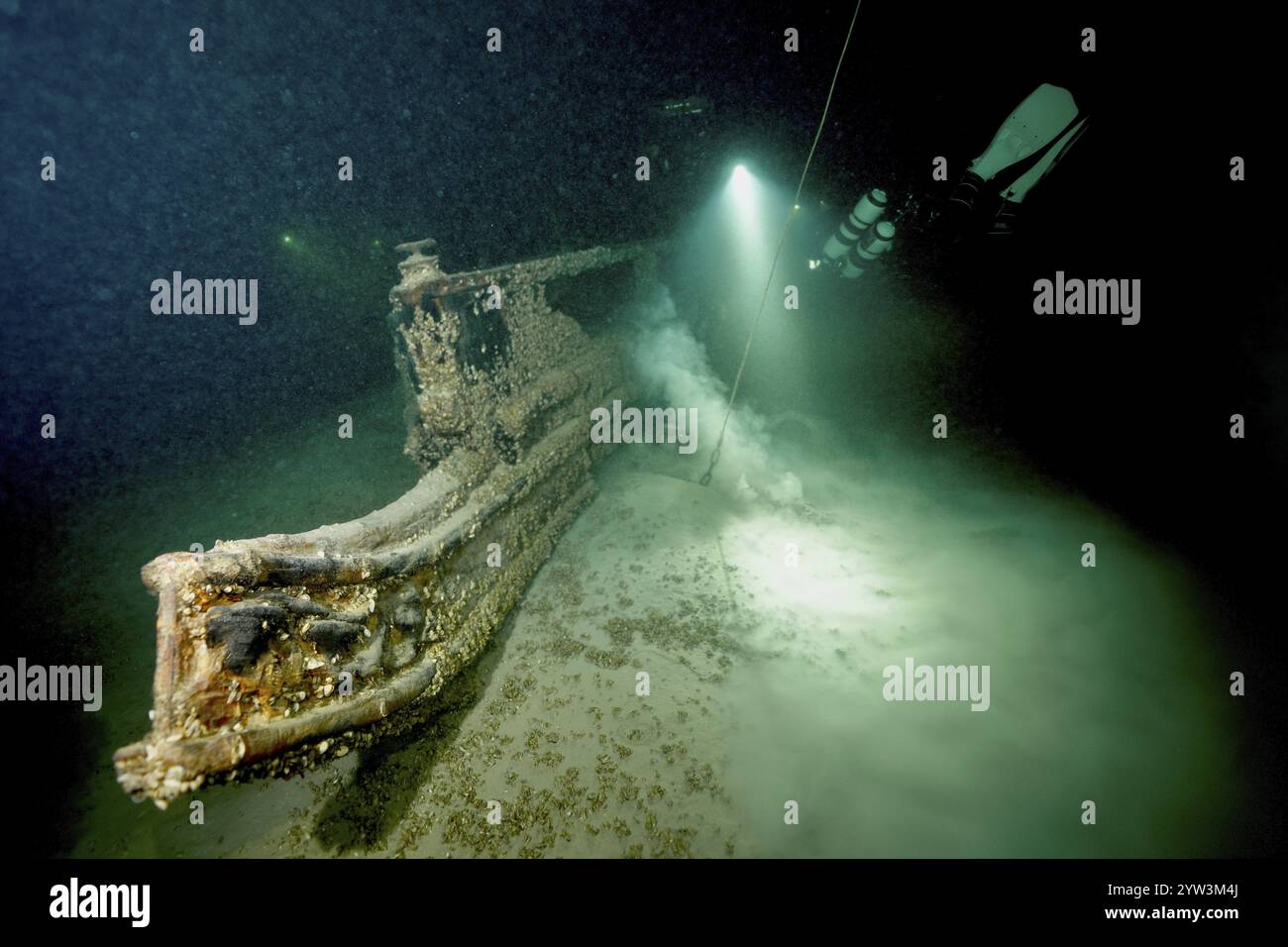 Underwater image of a diver approaching a shipwreck with a light source ...