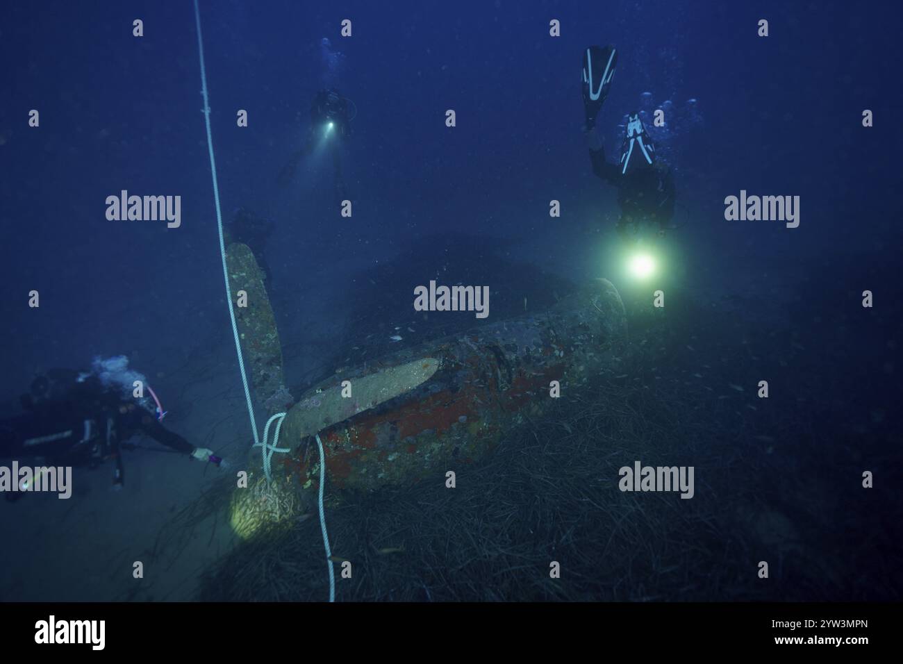 Divers illuminate an aircraft wreck from the Second World War during an ...