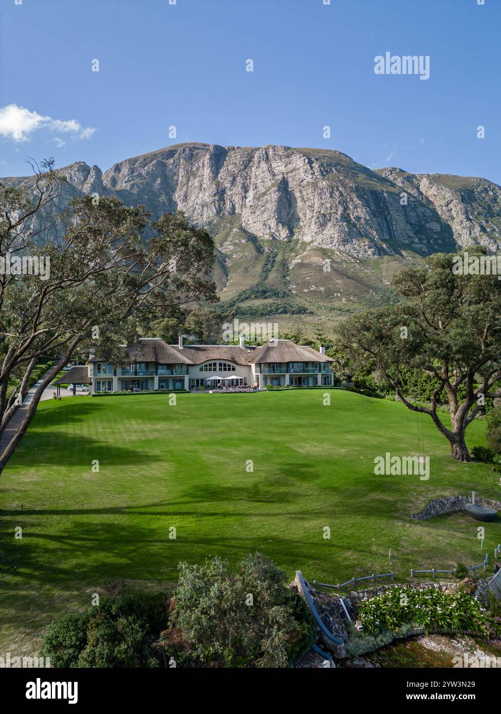 Large house at foot of high rocky mountain, building, bright green ...