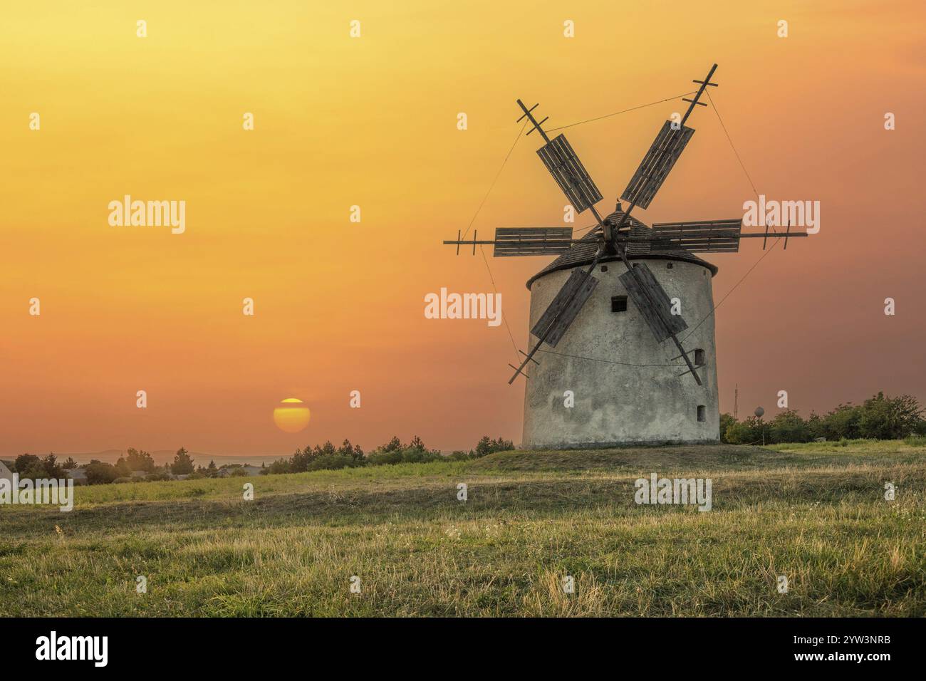 Windmill with wooden sails in a landscape with fields. Meadows and ...