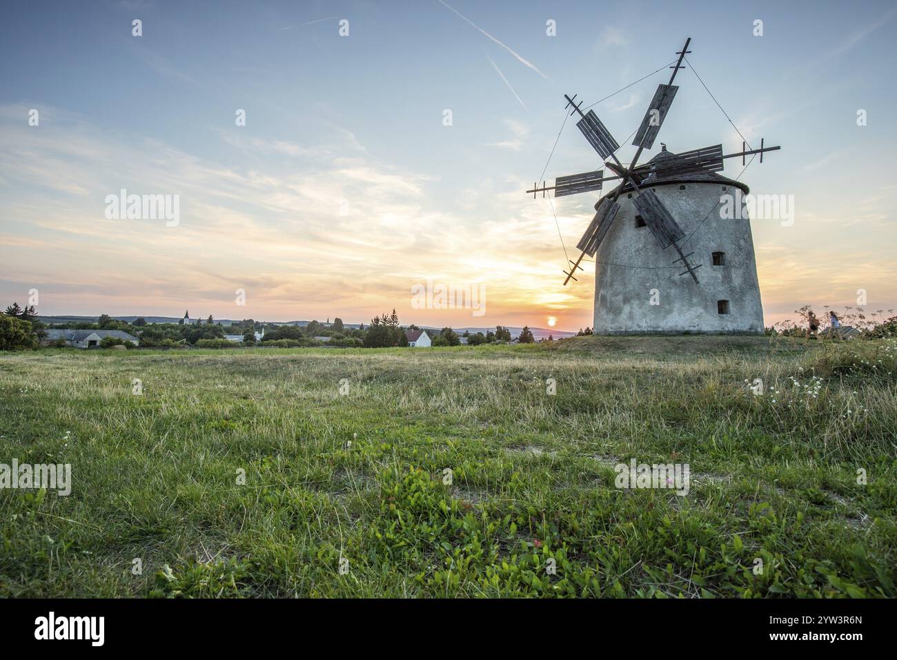 Windmill with wooden sails in a landscape with fields. Meadows and ...