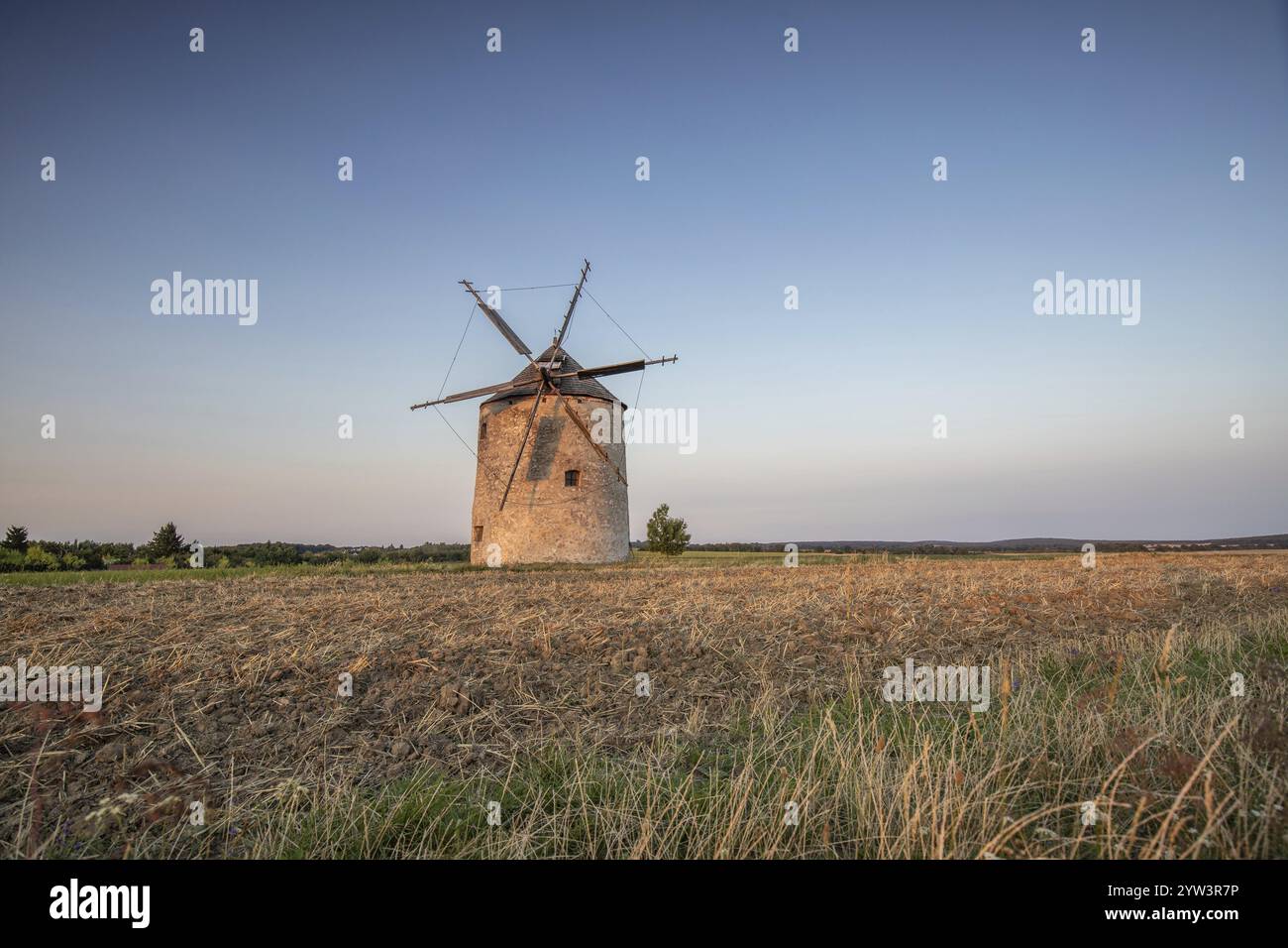 Windmill with wooden sails in a landscape with fields. Meadows and ...