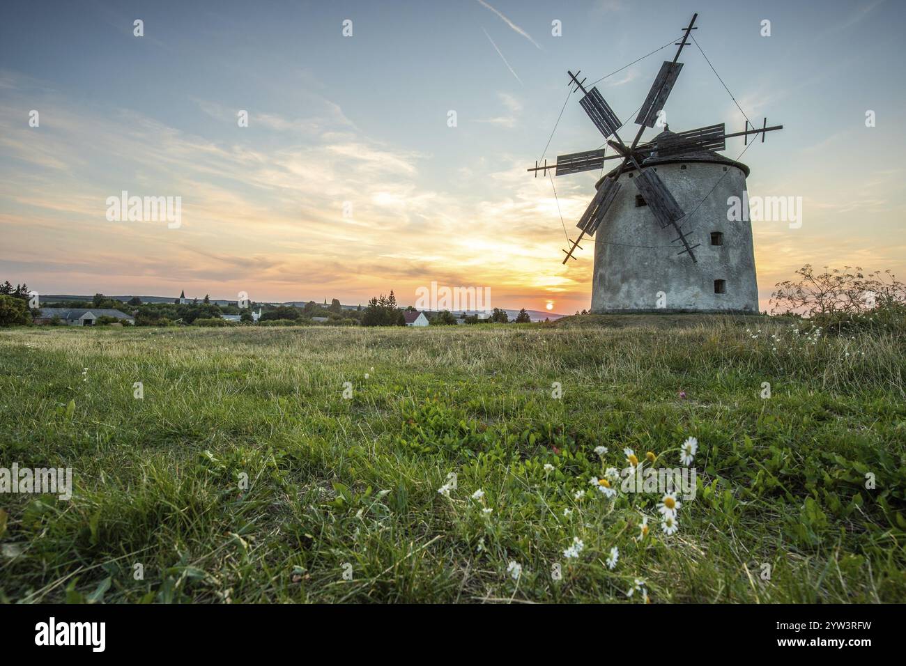 Windmill with wooden sails in a landscape with fields. Meadows and ...