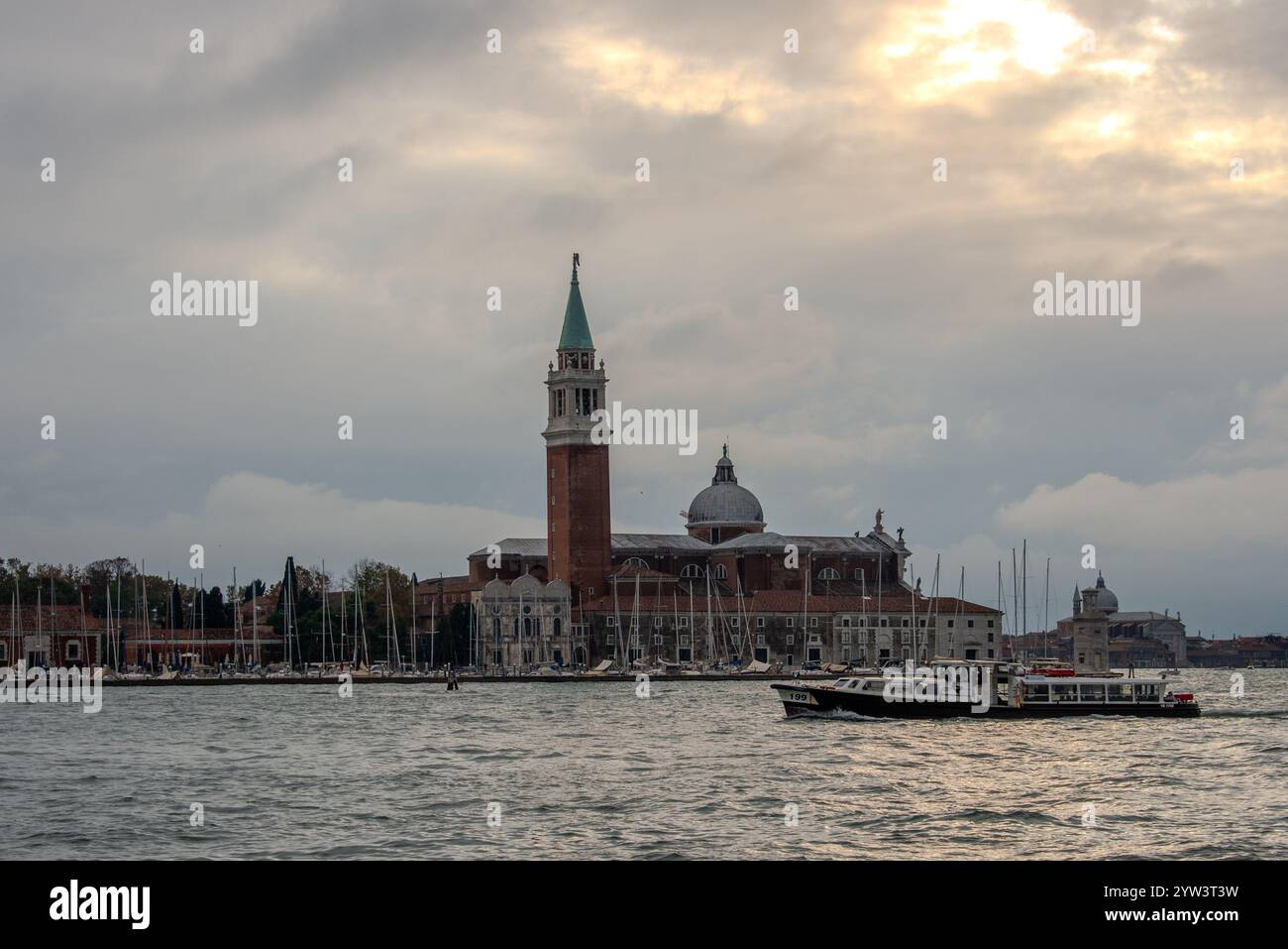 Clouds over Venice: A ferry boat crosses the lagoon towards the Canale Grande in front of the ...