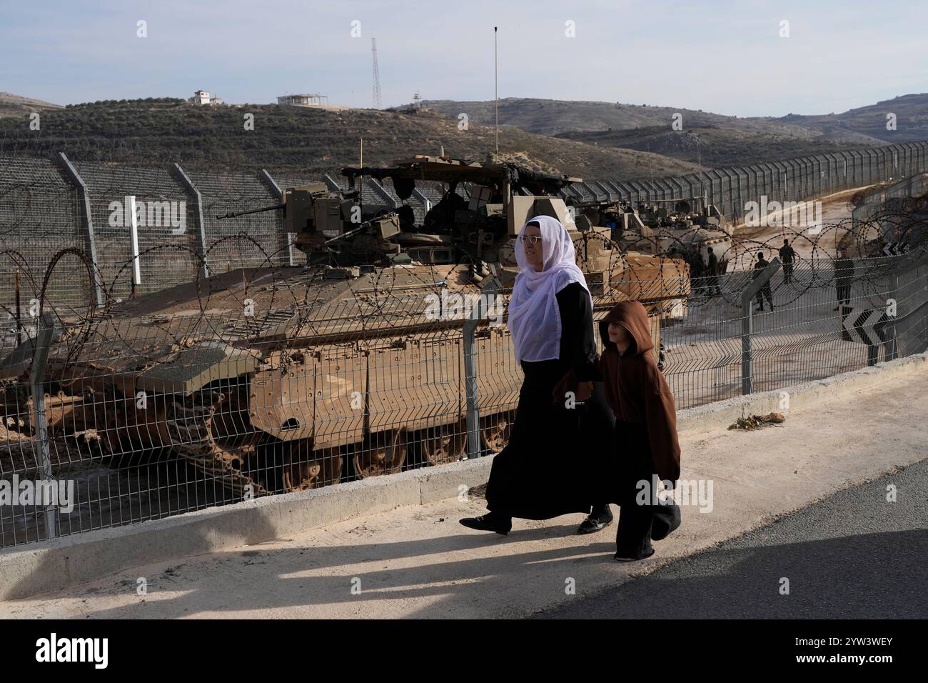 Locals walks next to Israeli armored vehicles parked near the so-called ...