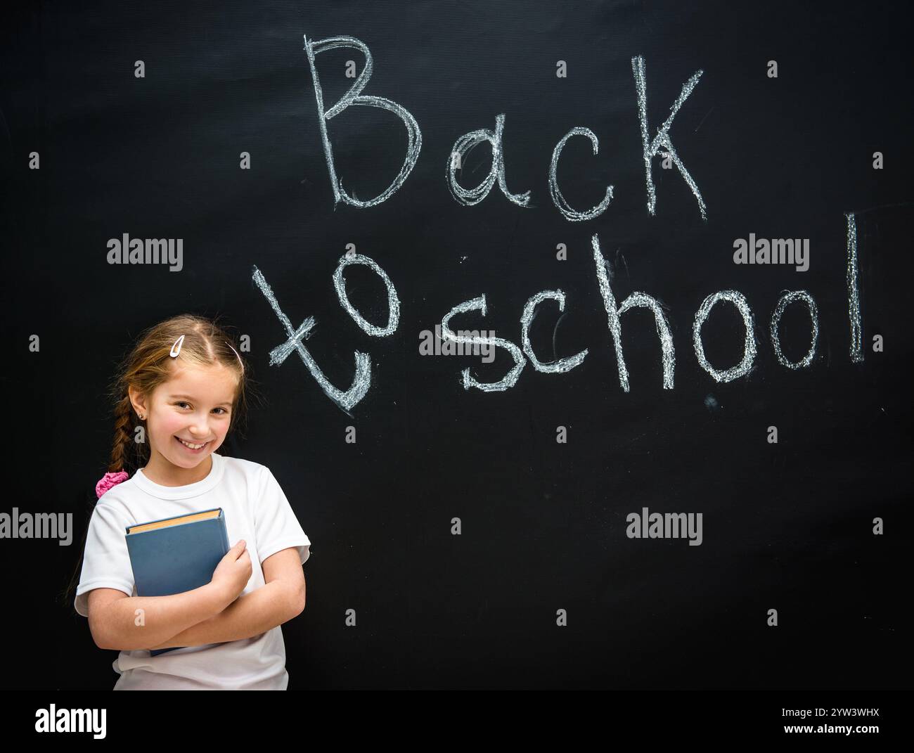 cute little girl with a blue book in hands smiling on black background ...