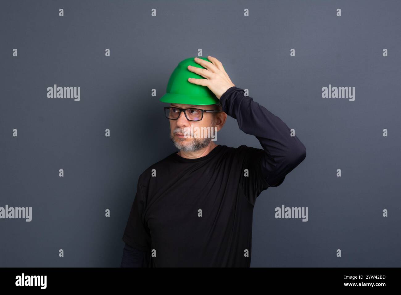 Portrait of a civil worker wearing a green helmet and black clothing ...