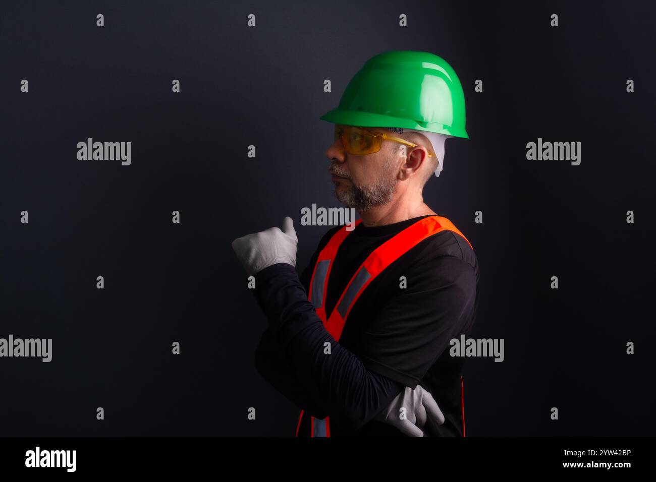 Photo of a civil worker wearing a green helmet, reflective vest and ...