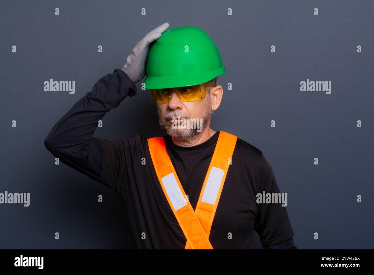 A civil worker wearing green hard hat, reflective vest and protective ...