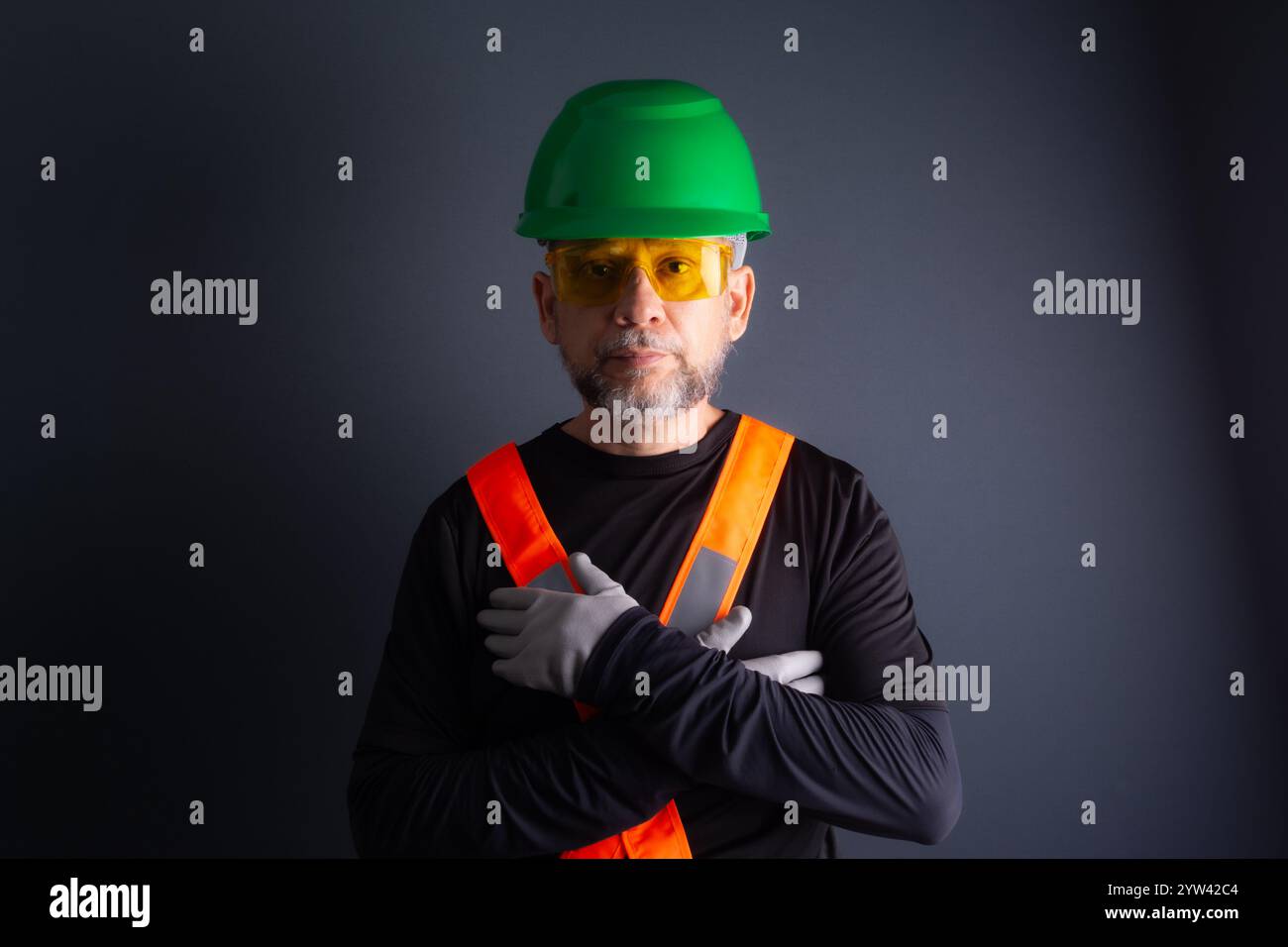 Photo of a civil worker wearing a green helmet, reflective vest and ...
