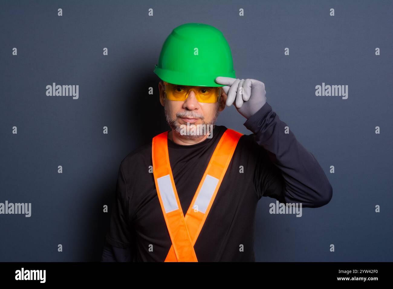 Photo of a civil worker wearing a green helmet, reflective vest and ...