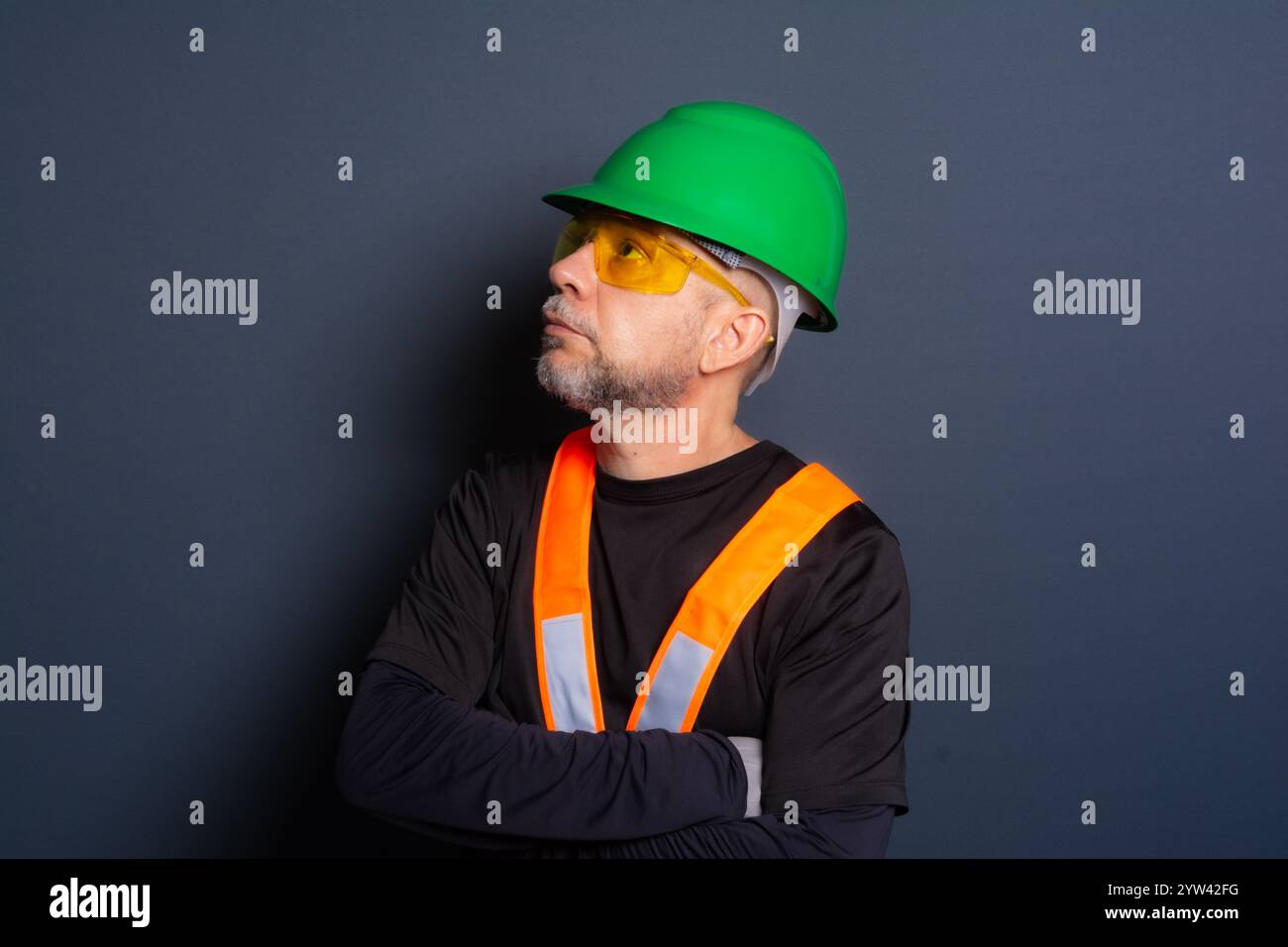 Photo of a civil worker wearing a green helmet, reflective vest and ...