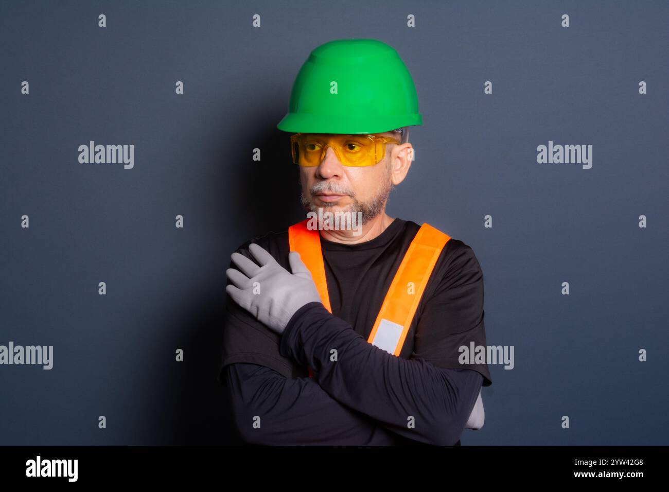 Photo of a civil worker wearing a green helmet, reflective vest and ...