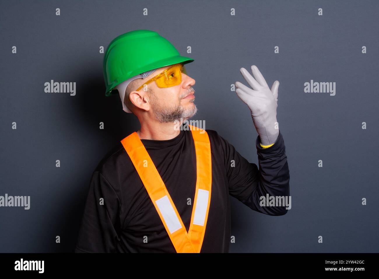 Photo of a civil worker wearing a green helmet, reflective vest and ...