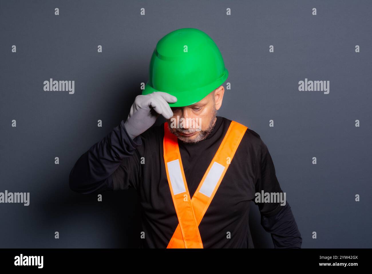 Photo of a civil worker wearing a green hard hat and reflective vest ...