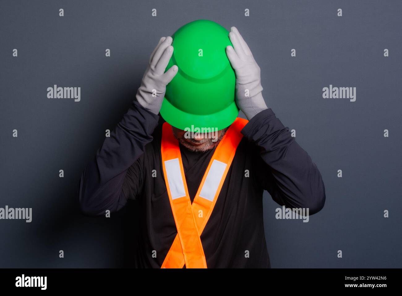 Photo of a civil worker wearing a green hard hat and reflective vest ...