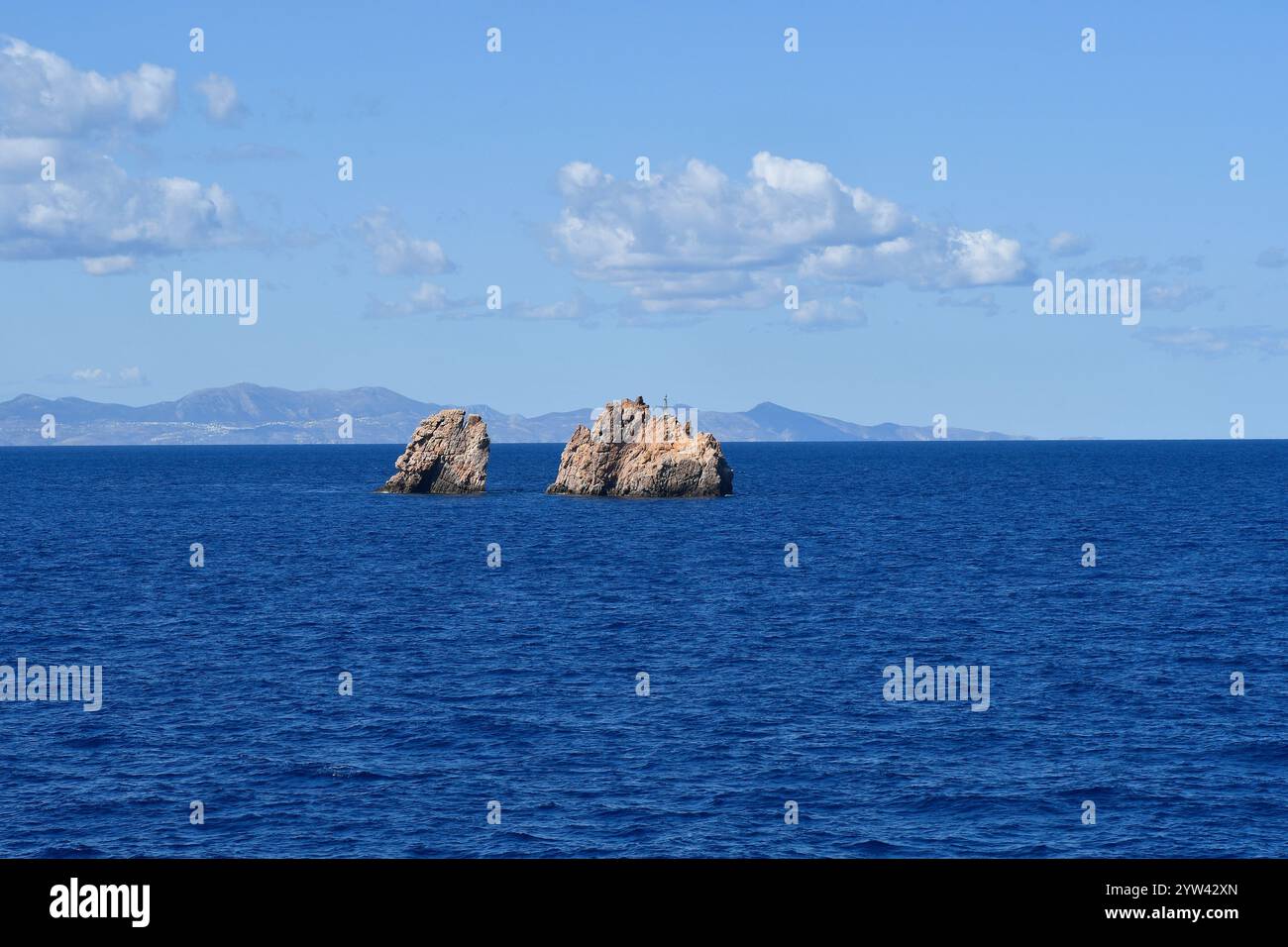 Greece, rocks in the sea at the entrance to Paros with a lighthouse for ...