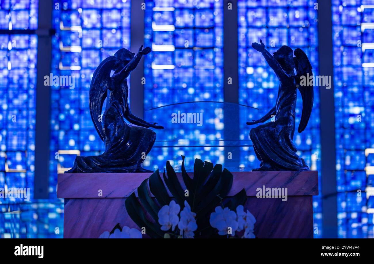 Close-up on pair of metal statues of angels against a blue stained ...