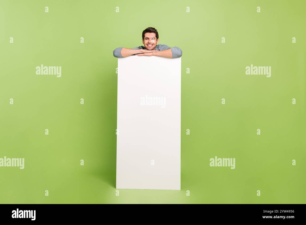 Full body photo of cheerful young man stand behind long white placard ...