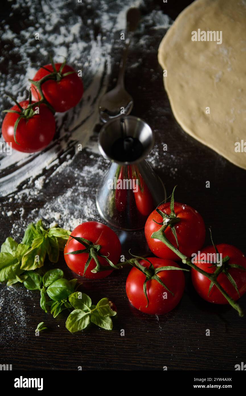 Cluster of ripe tomatoes and fresh basil on flour-dusted surface for ...