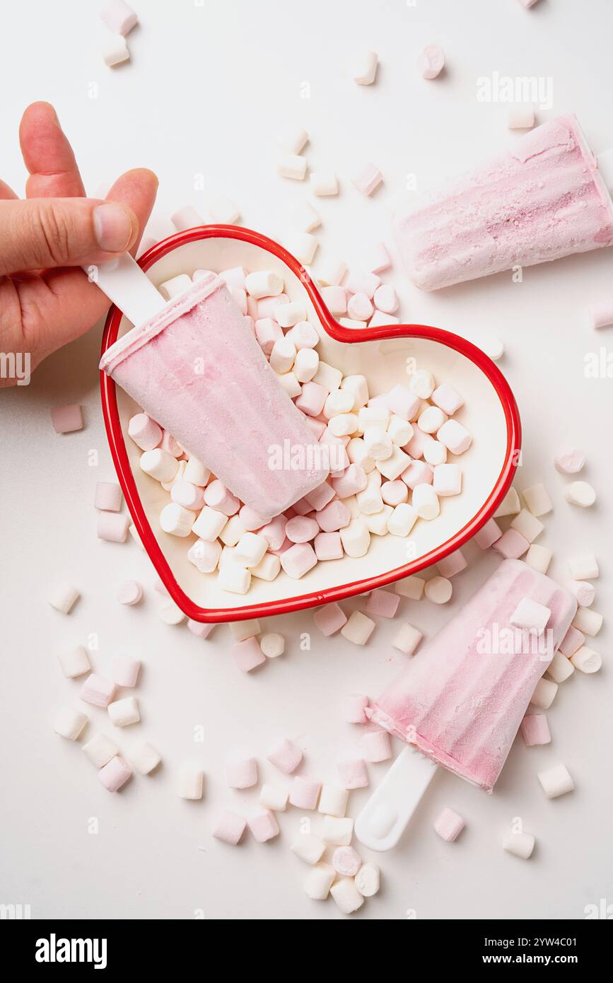Pink ice cream popsicles arranged with marshmallow toppings, placed in ...