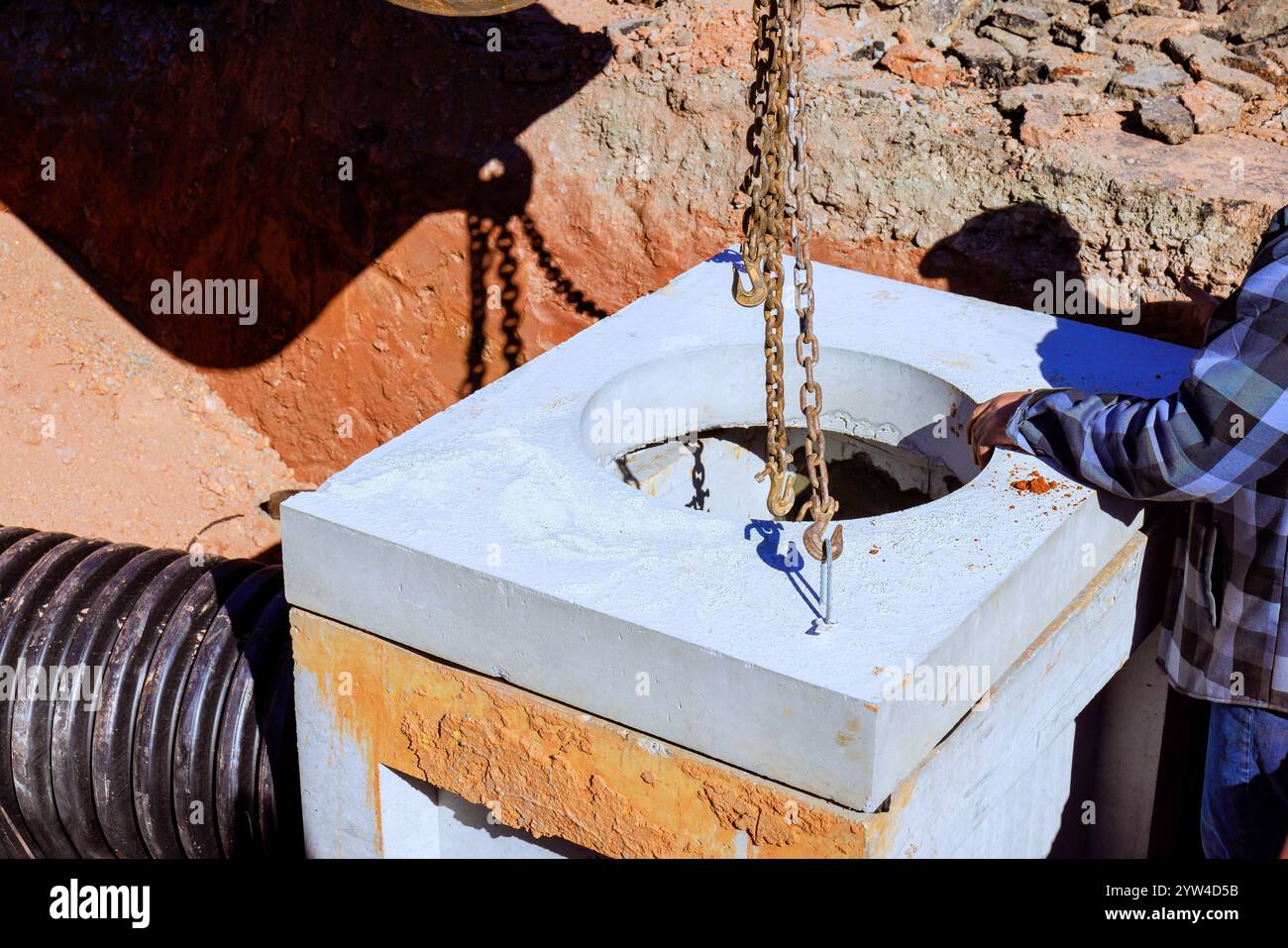 Worker operates crane to lift concrete slab to drainage system well at ...