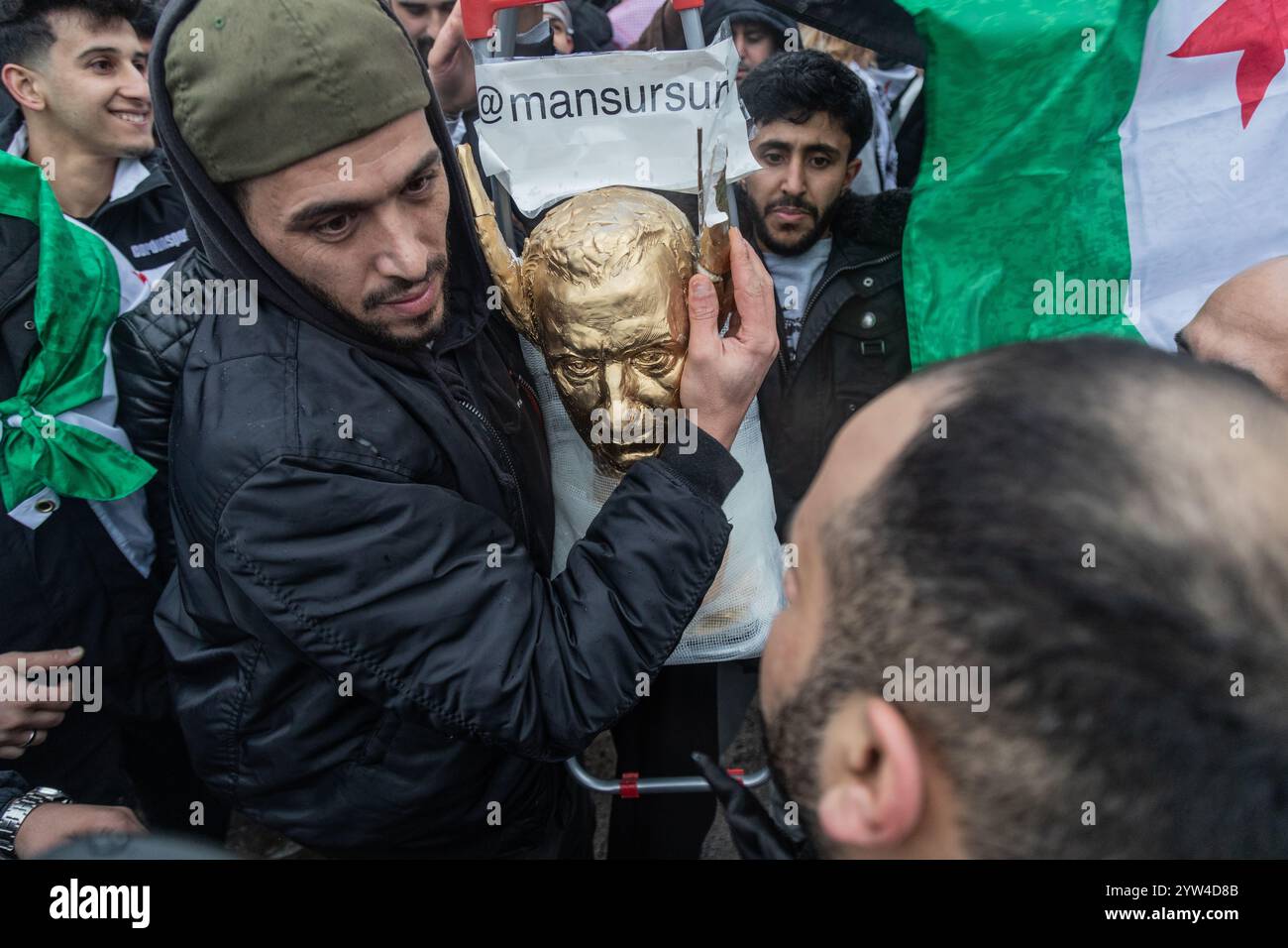A man holds up a gold colored head of Bashar al-Assad during the ...