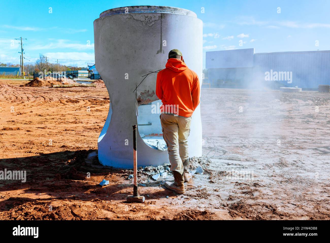 Construction worker in an orange hoodie is breaking down concrete ...