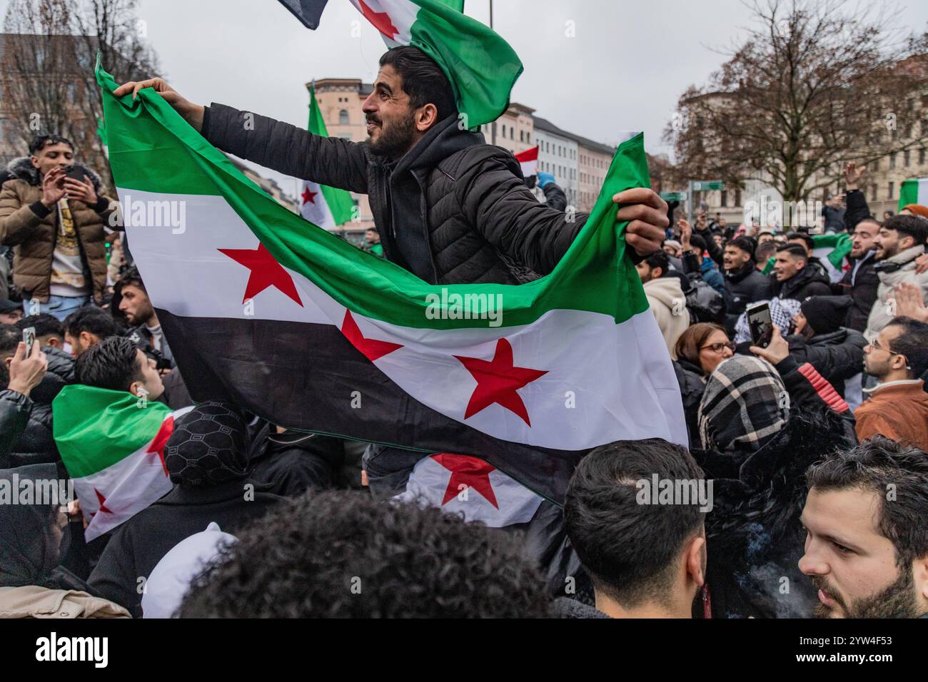 Berlin, Germany. 08th Dec, 2024. A young man holds up a Free Syrian ...