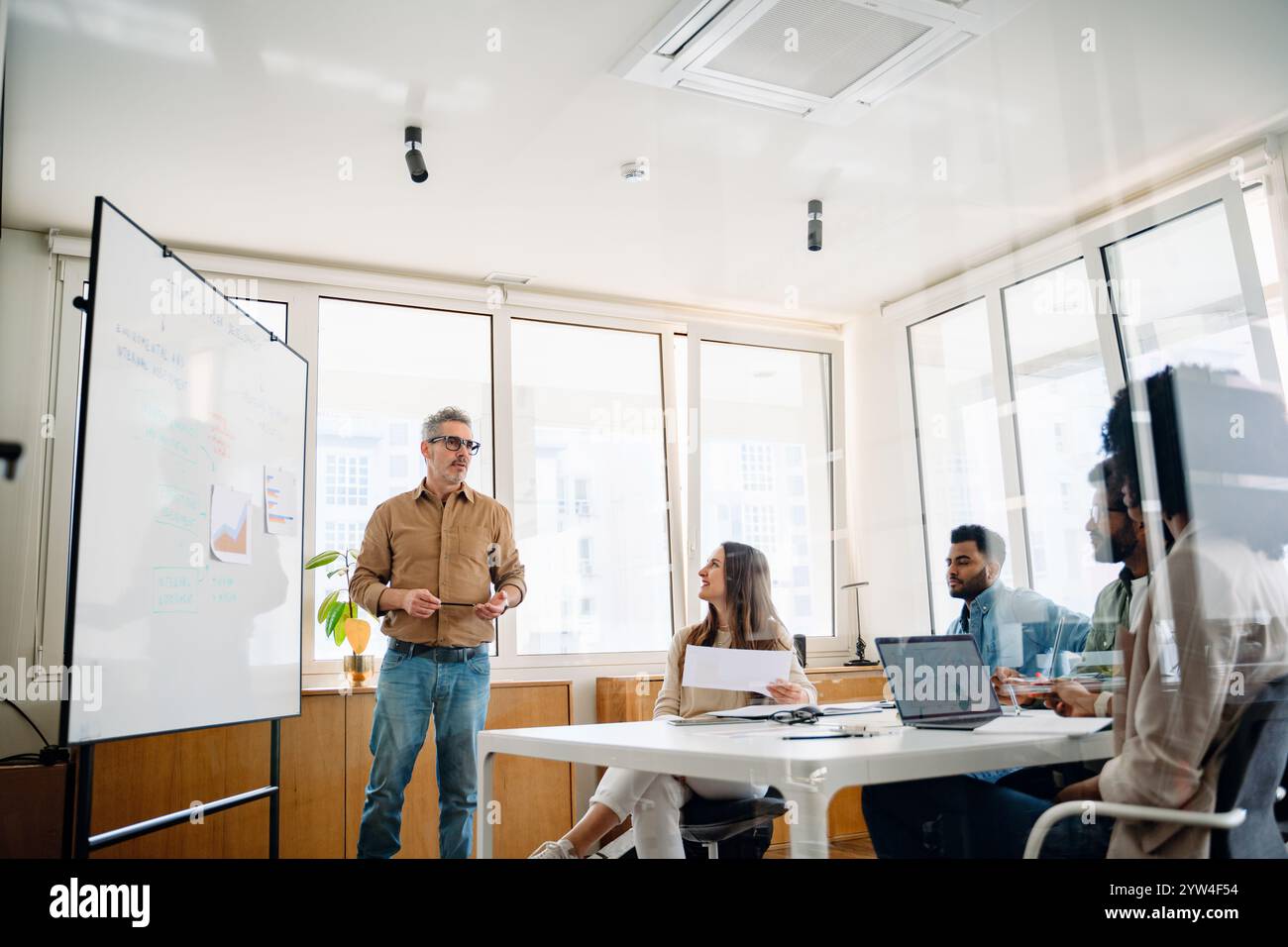 A seasoned executive confidently addresses his multiethnic team in a ...