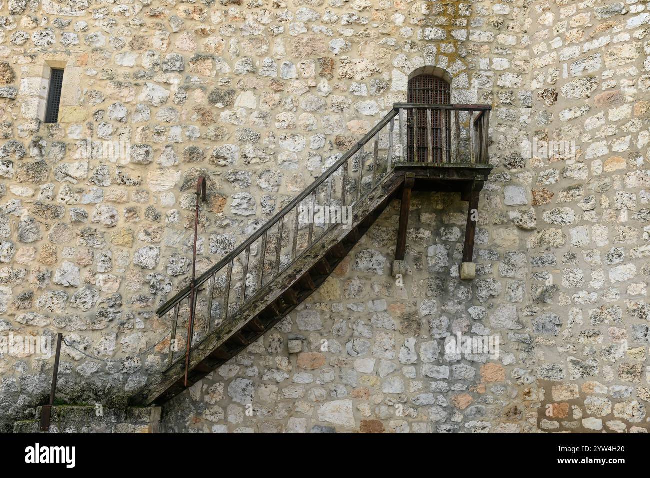 A close-up of Torija Castle's stone wall, featuring a wooden staircase ...