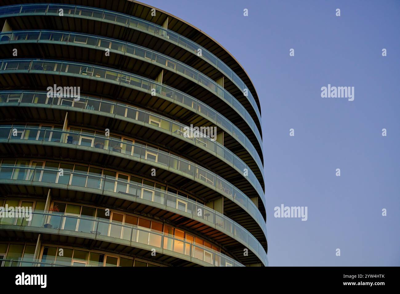 Modern round residential building with balconies at sunset ...