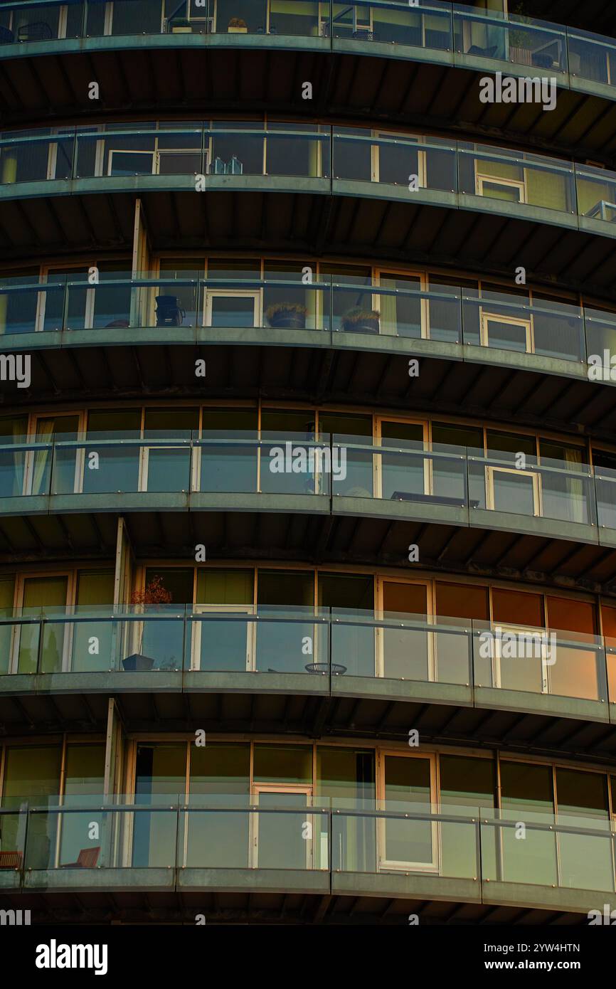 Modern round residential building with balconies at sunset ...