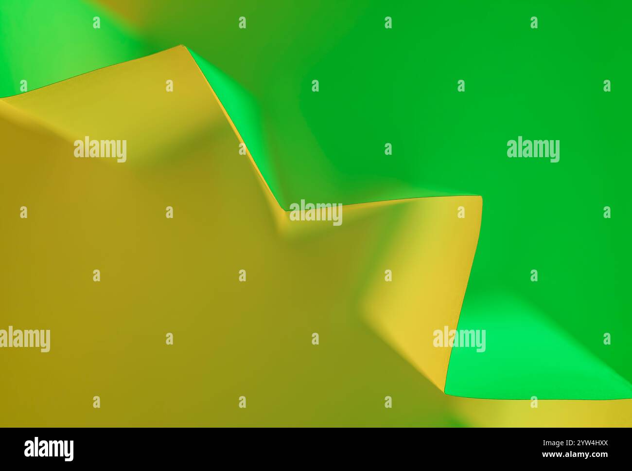 Folded paper illuminated by green and yellow coloured lights to create ...