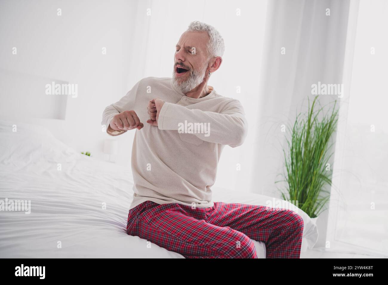 Elderly man in pajamas waking up feeling refreshed and relaxed in a ...