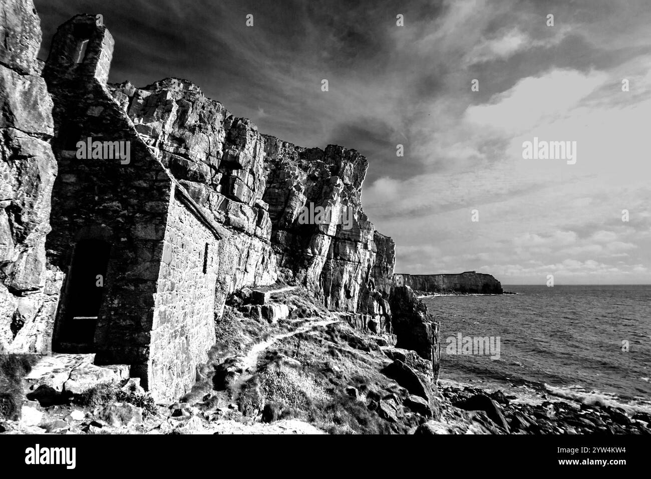Dramatic black and white view of the small St Govan’s Chapel, hidden ...