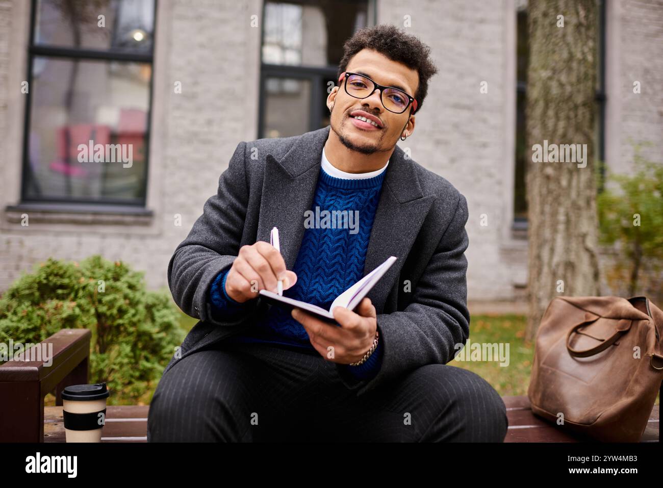 A handsome man sits comfortably writing in his notebook, surrounded by ...