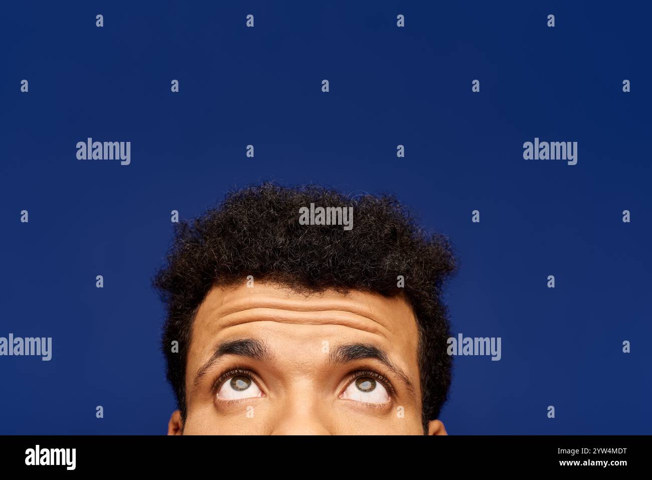 A handsome man looks thoughtfully upwards, his expression hinting at ...