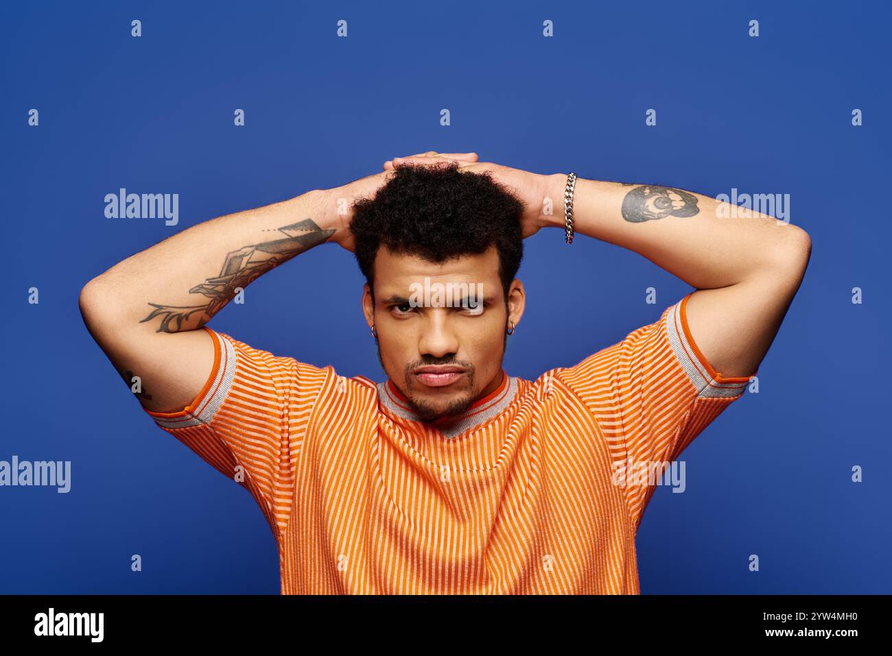 A stylish man with tattoos showcases a strong pose, displaying his ...