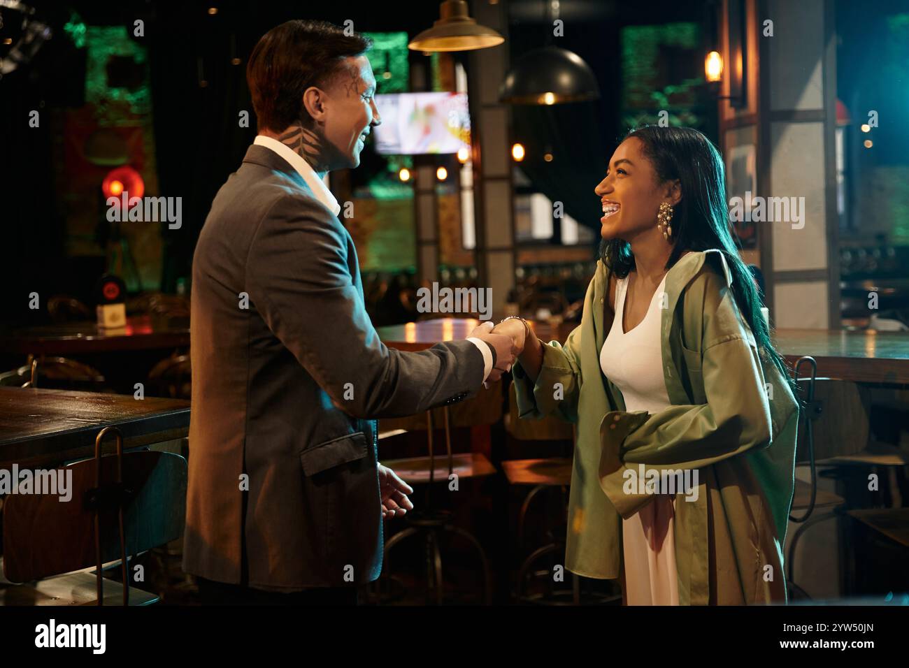A young couple shares a joyful moment at a bar during their date night ...