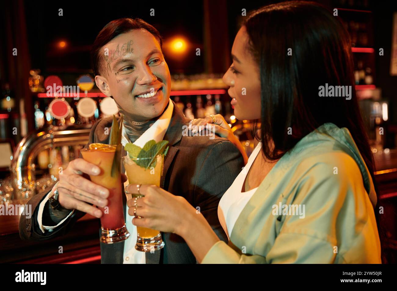 A young couple shares a joyful moment while toasting with colorful ...