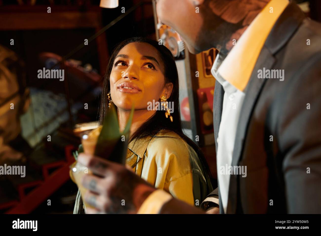 A young couple shares an intimate moment at a vibrant bar while sipping ...