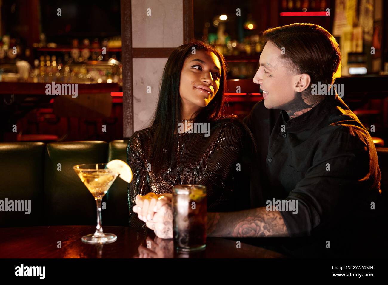 A young couple shares a cozy moment at a lively bar, immersed in ...