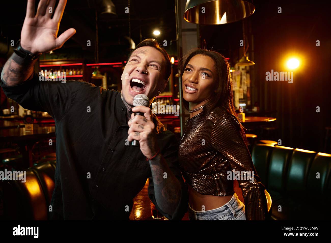 A young couple shares joy while having fun at a bar, singing together ...