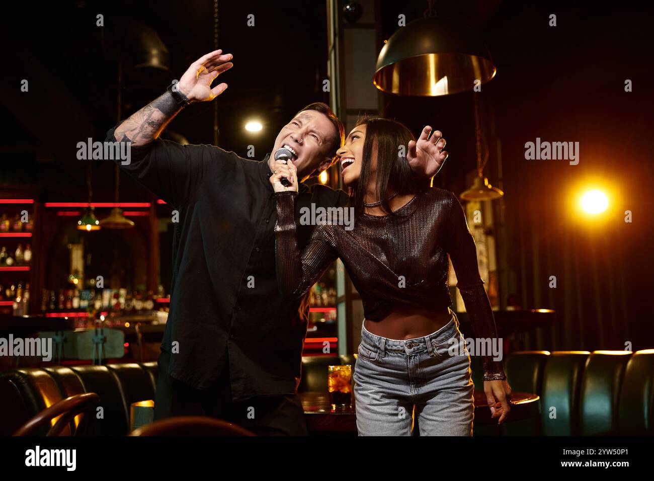 A young couple shares a fun moment singing passionately on a karaoke ...