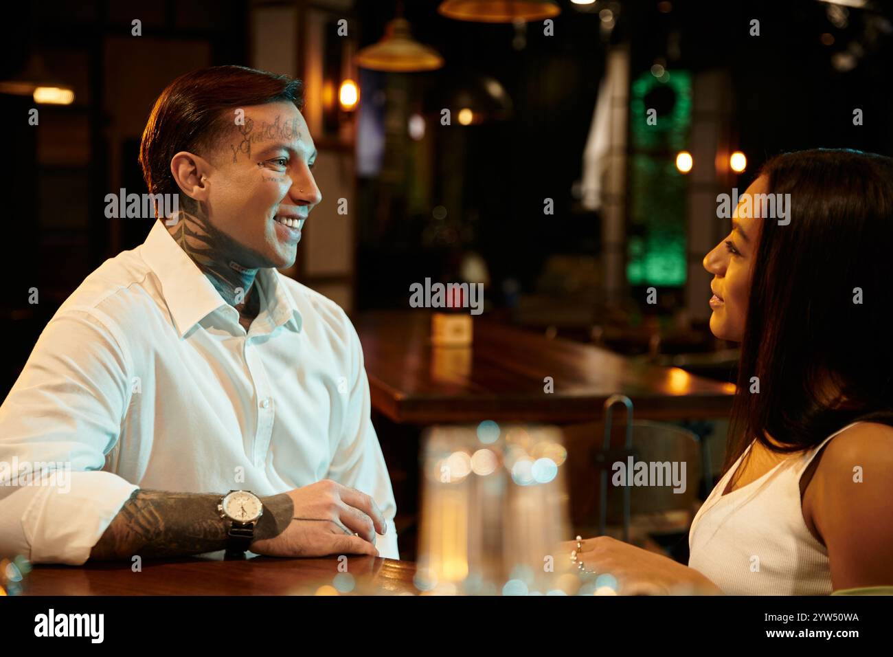 A young couple shares smiles and connection over drinks on a night out ...